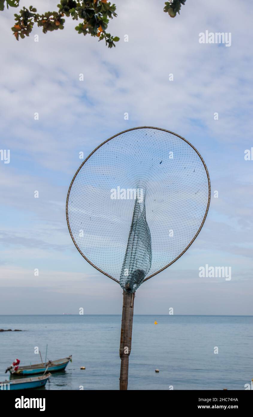 Vertical shot of a fishing net on a beach with beautiful clouds behind ...