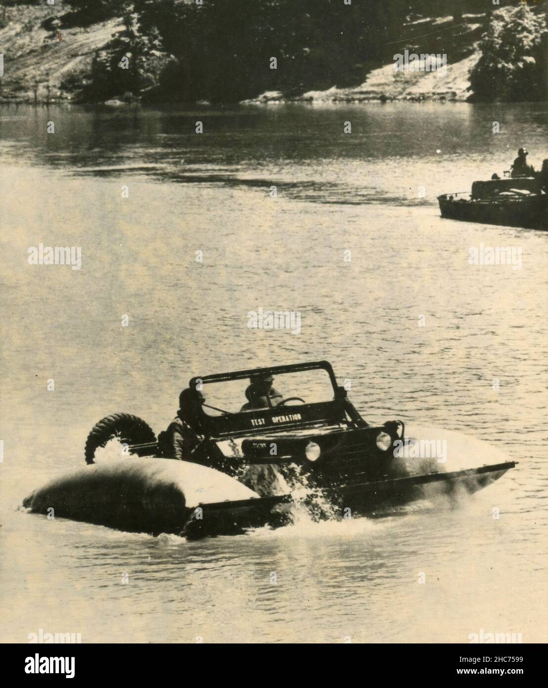 US Army Jeep supported by inflated plastic floats moves across the lake ...