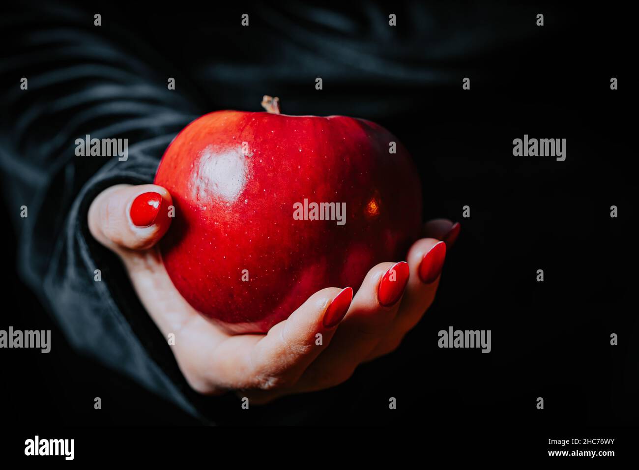 Witch woman in black offers red apple as symbol of temptation, poison ...
