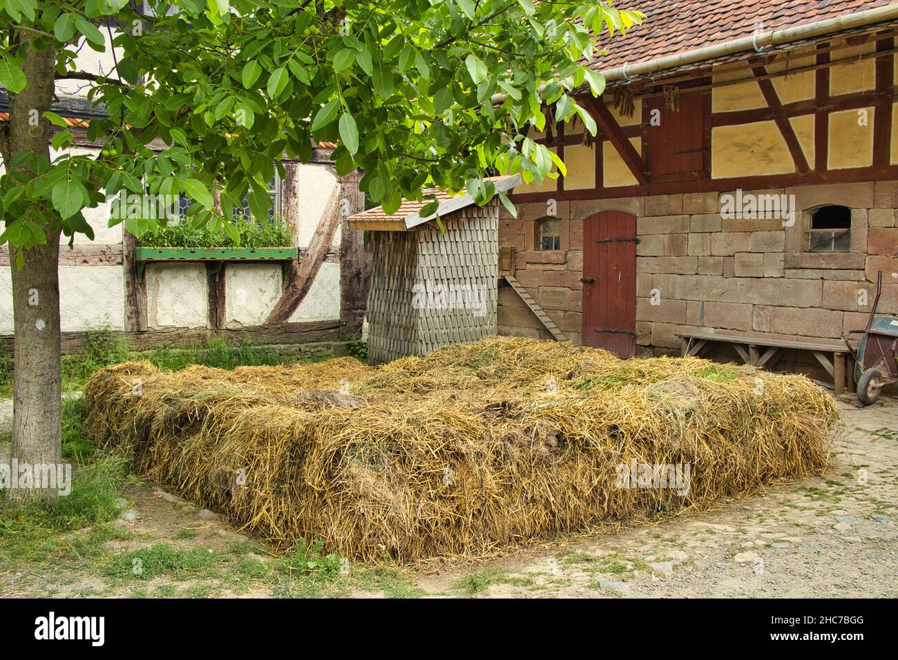 Rural view of a village farm with an outdoor toilet and hey in the yard ...