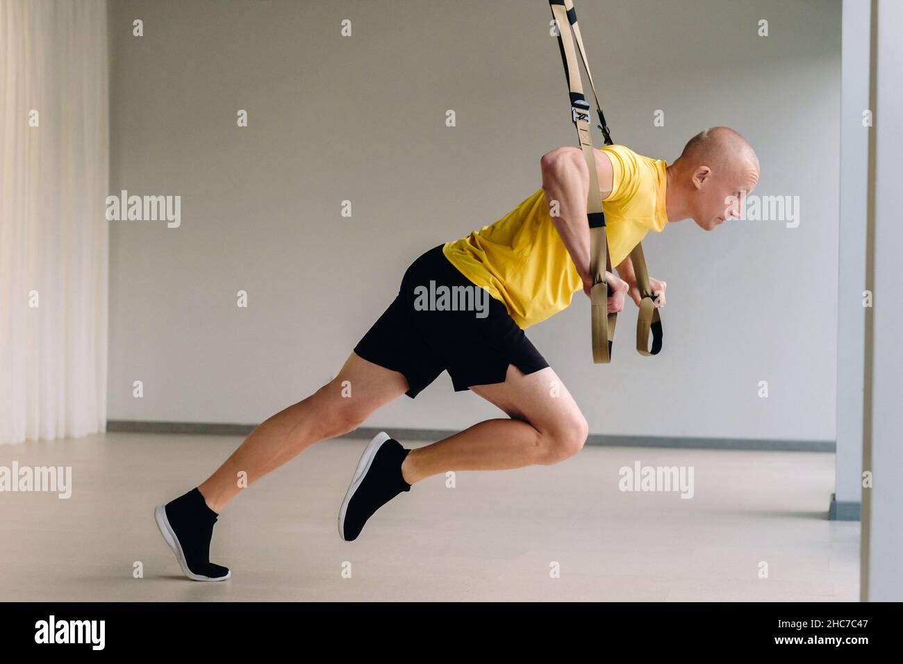 A focused male athlete performing an exercise on functional loops in ...