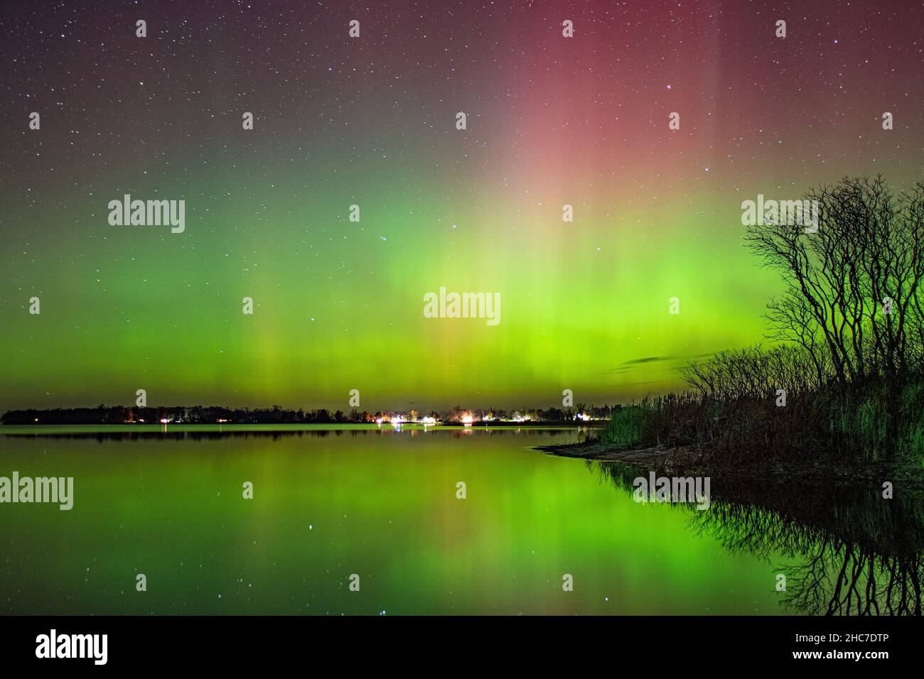 Stunning view of green northern lights reflected on a tranquil lake at ...