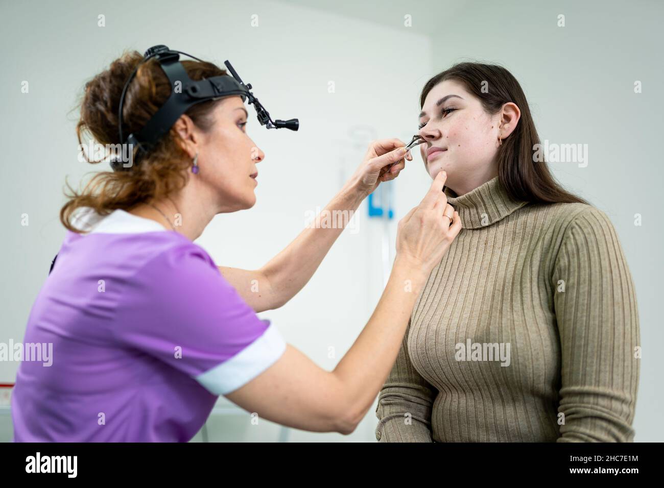 Female ENT doctor examines patient's sinuses with medical instrument in ...