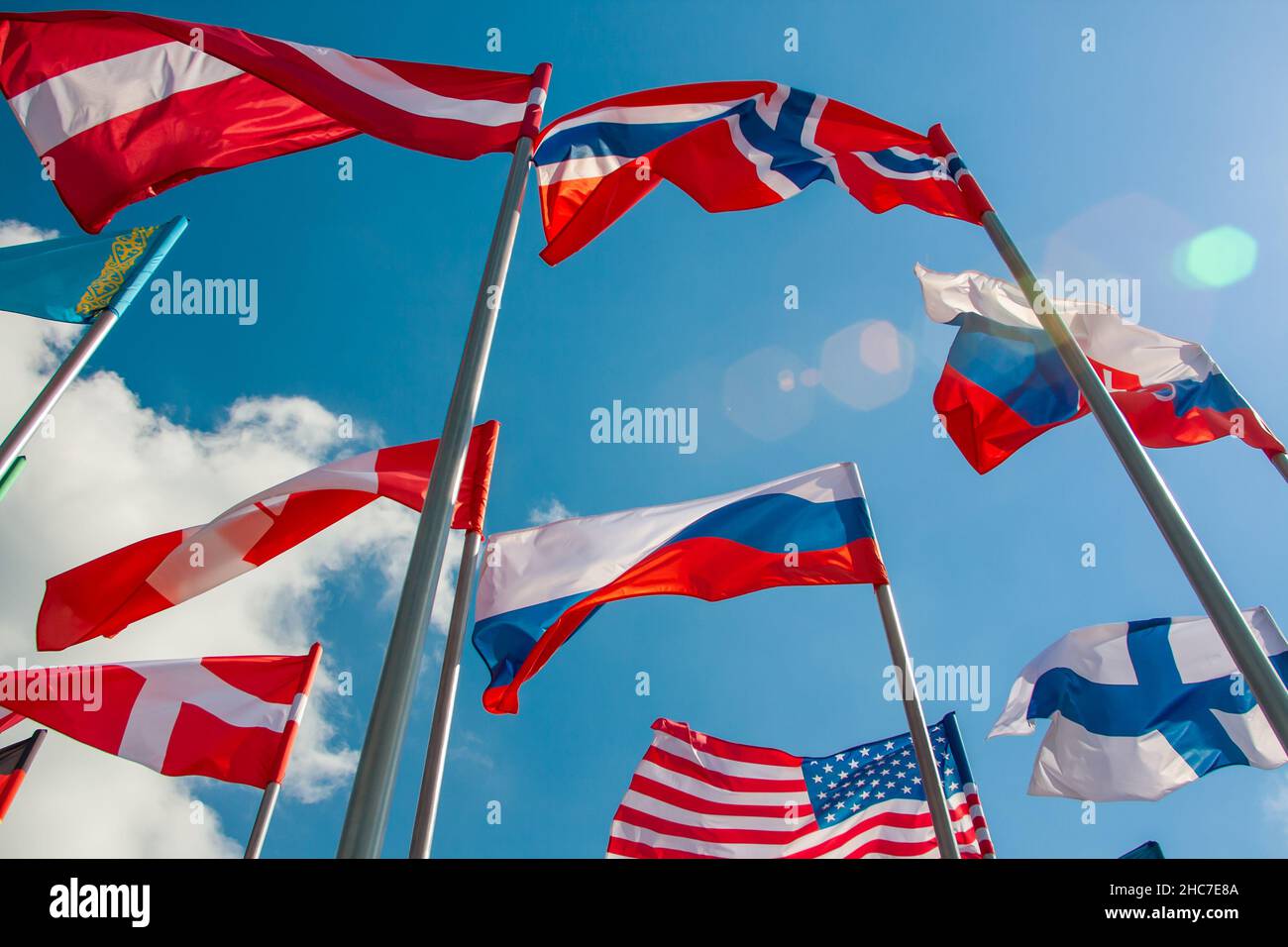 Bright flags of different countries against the blue sky and clouds ...