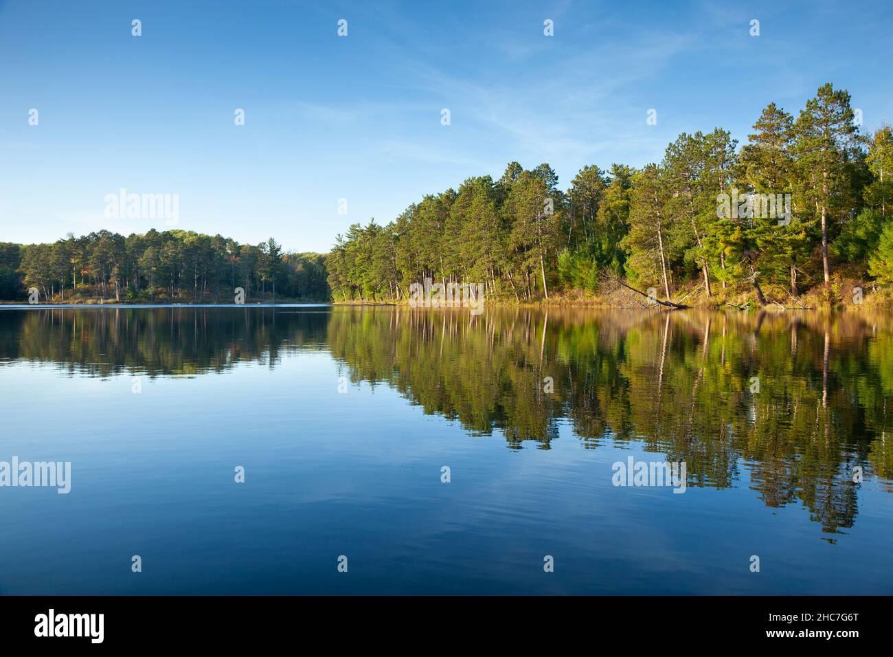 Beautiful calm northern Minnesota lake under blue sky with trees along ...