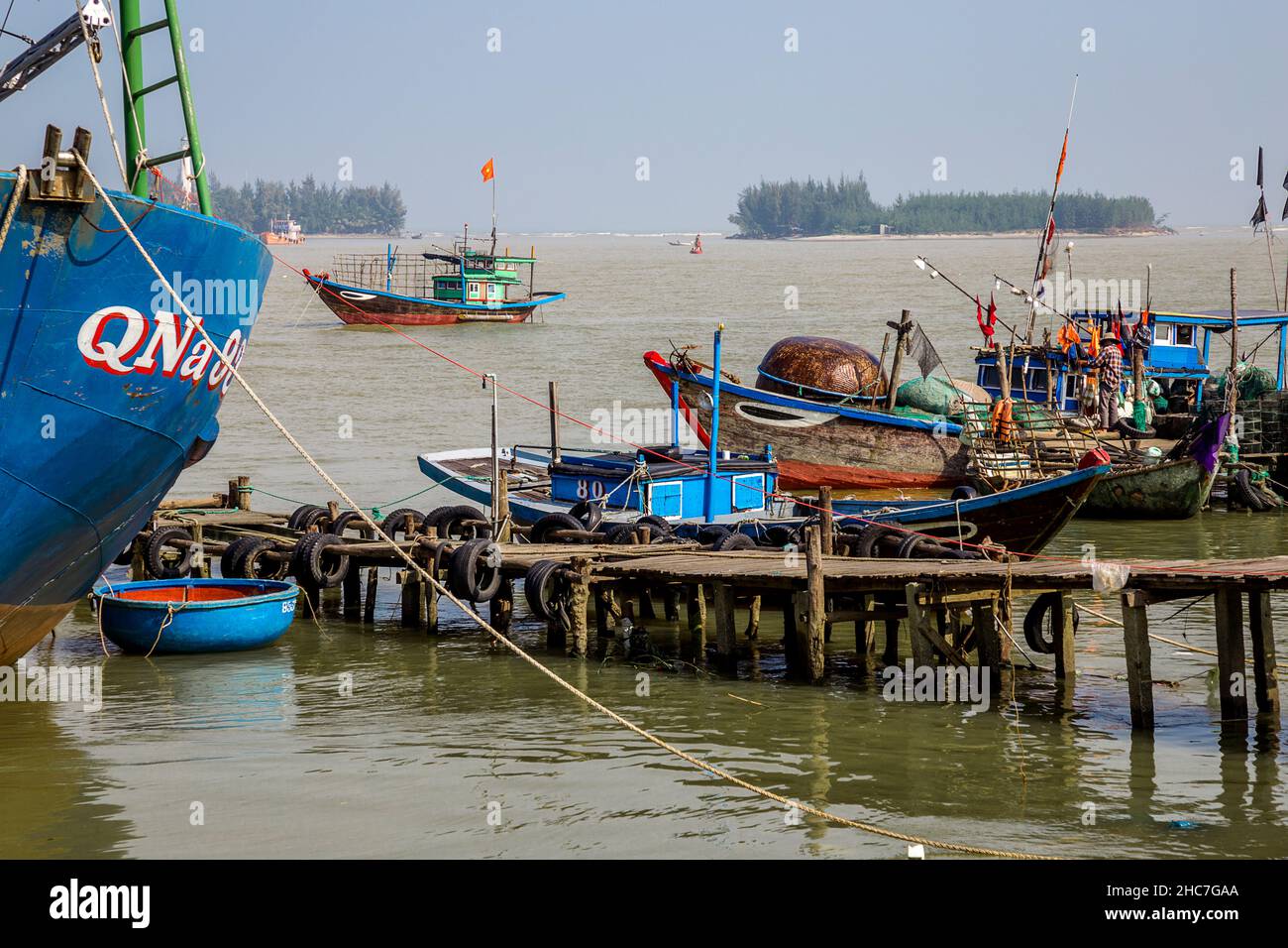 Big blue trawler in front of a wood dock with many fish nets and traps ...