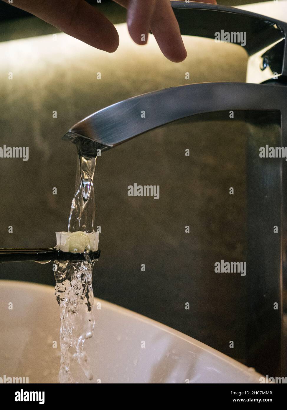 Toothbrush under running water from a steel tap Stock Photo - Alamy