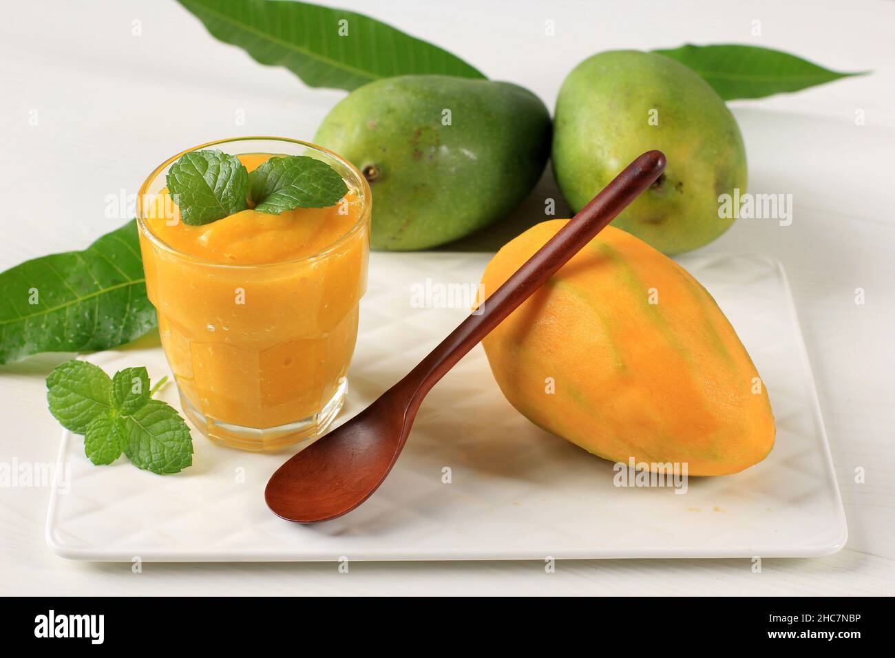 Mango Smoothie/Mango Lassi in a Glass on White Table with Mint leaves ...