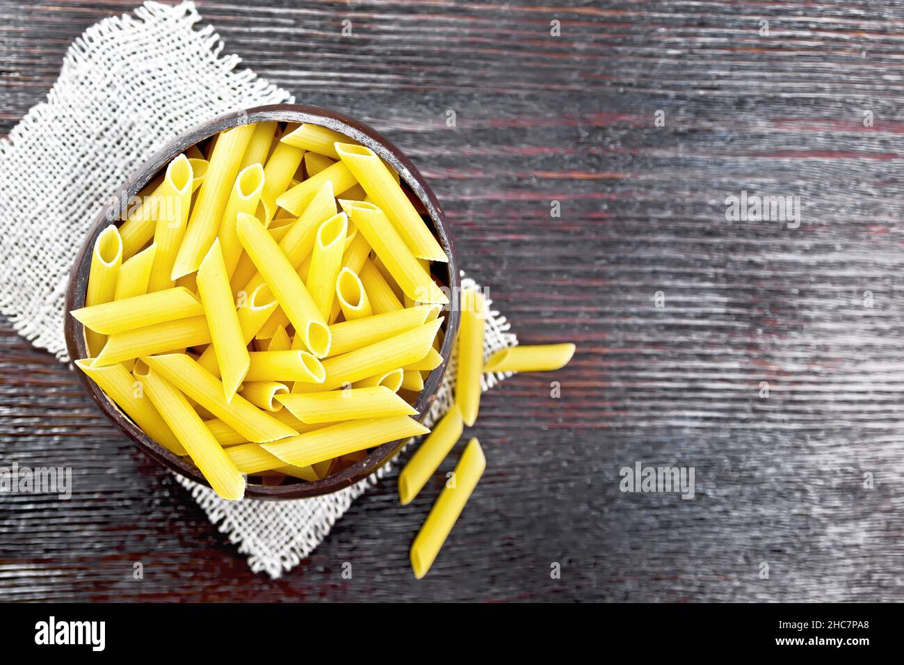 Wheat flour penne pasta in a bowl of coconut shells on sacking on a ...