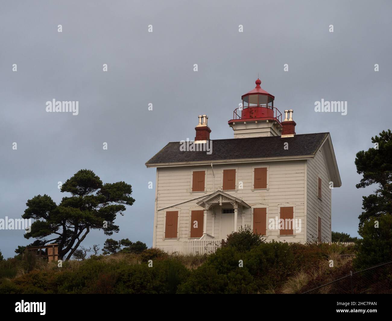 Two-story white wooden Yaquina Bay lighthouse with shuttered windows ...