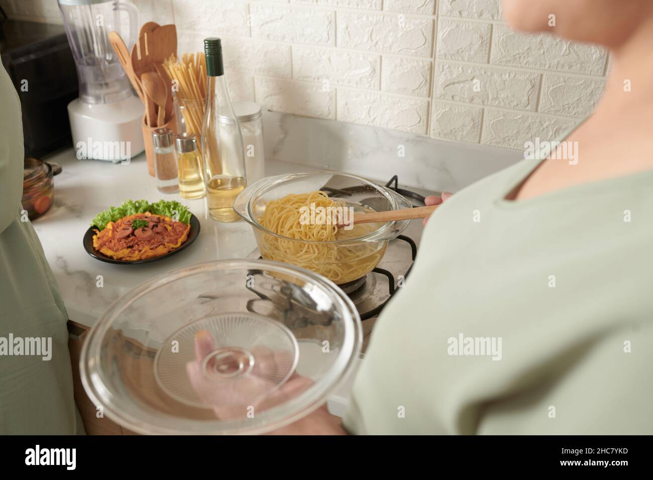 Senior woman cooking spaghetti for dinner with friends Stock Photo - Alamy