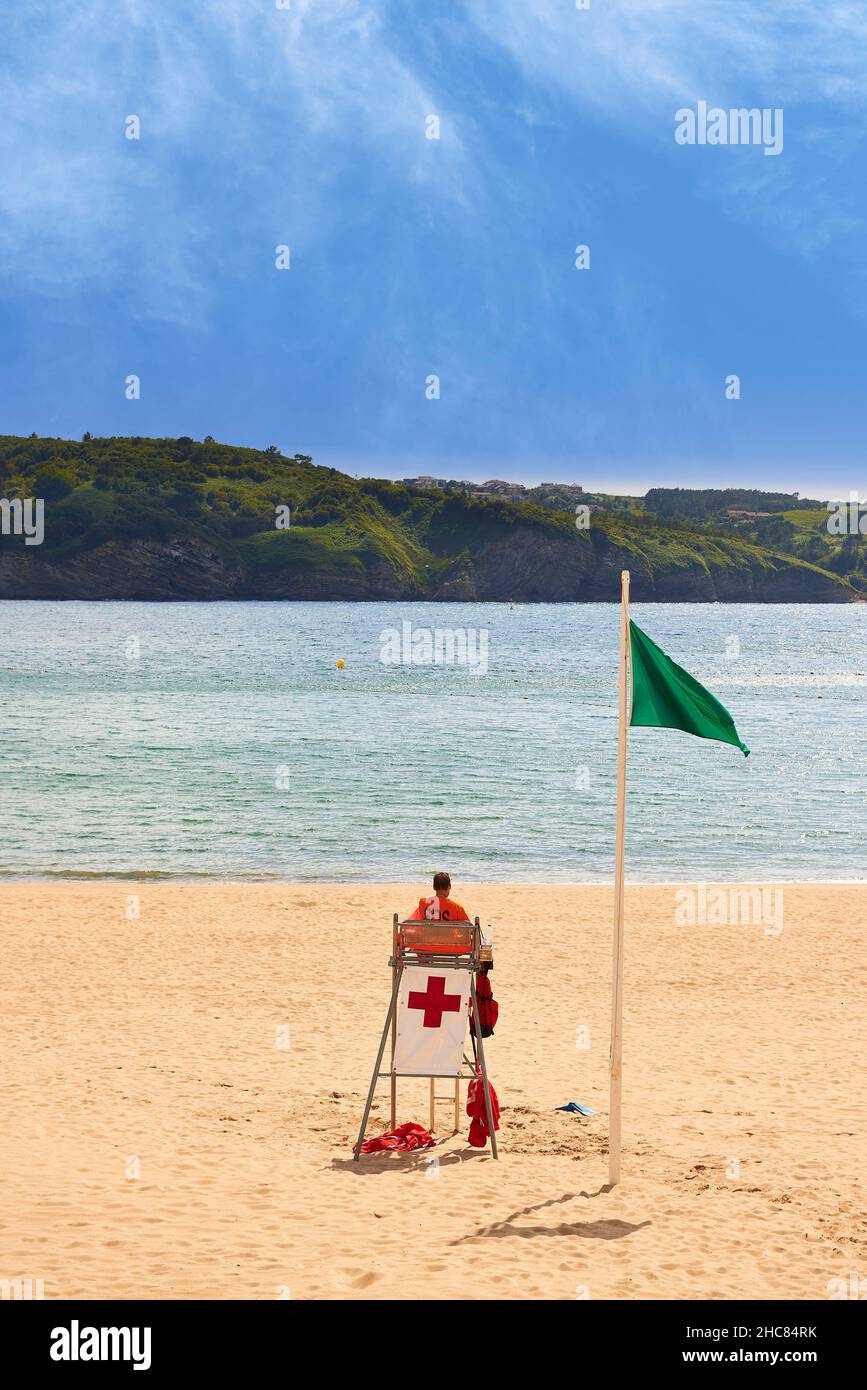 Red cross lifeguard guarding the beach with green flag waving Stock ...