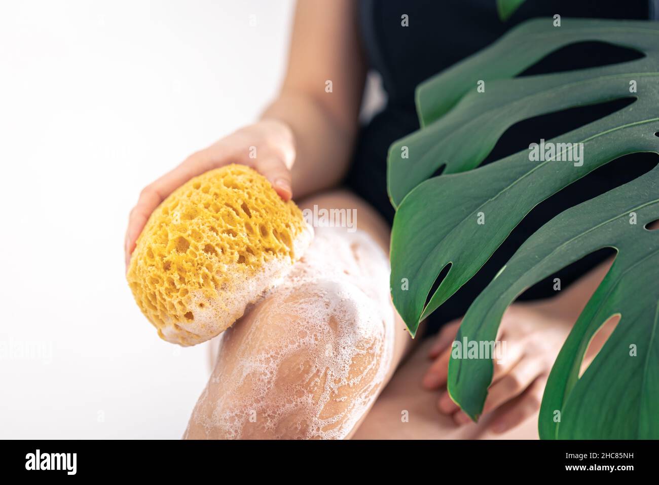 Young woman washing legs with yellow sponge and soap foam Stock Photo ...