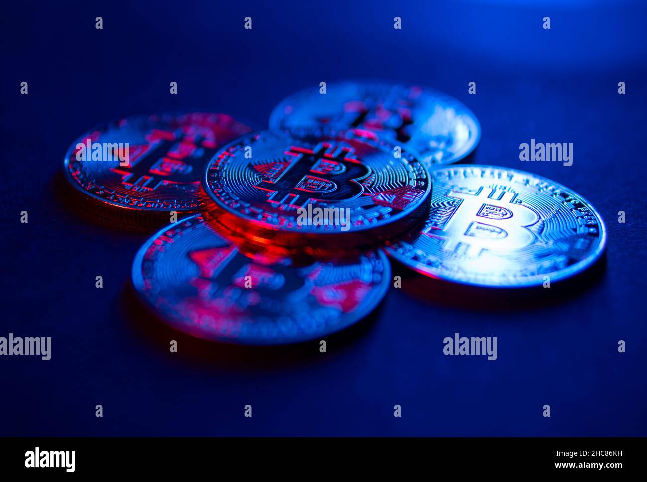 The coins of Bitcoin are on a dark Surface. Purple and pink neon light ...