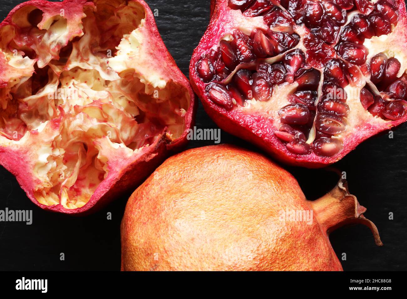 Macro photography of two organic pomegranates one whole and the other ...