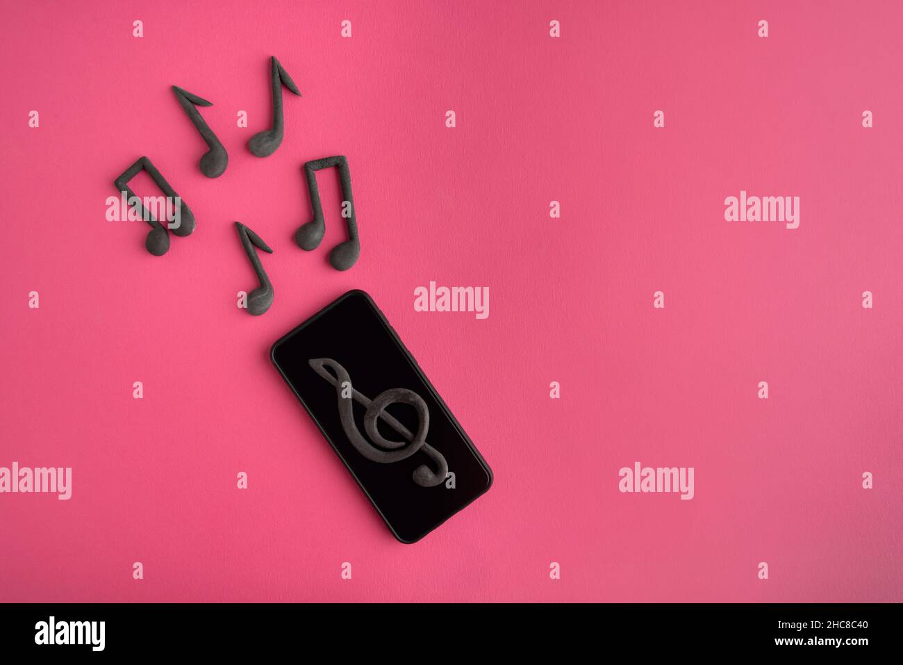 Smartphone, treble clef and musical note on pink background. Music apps ...
