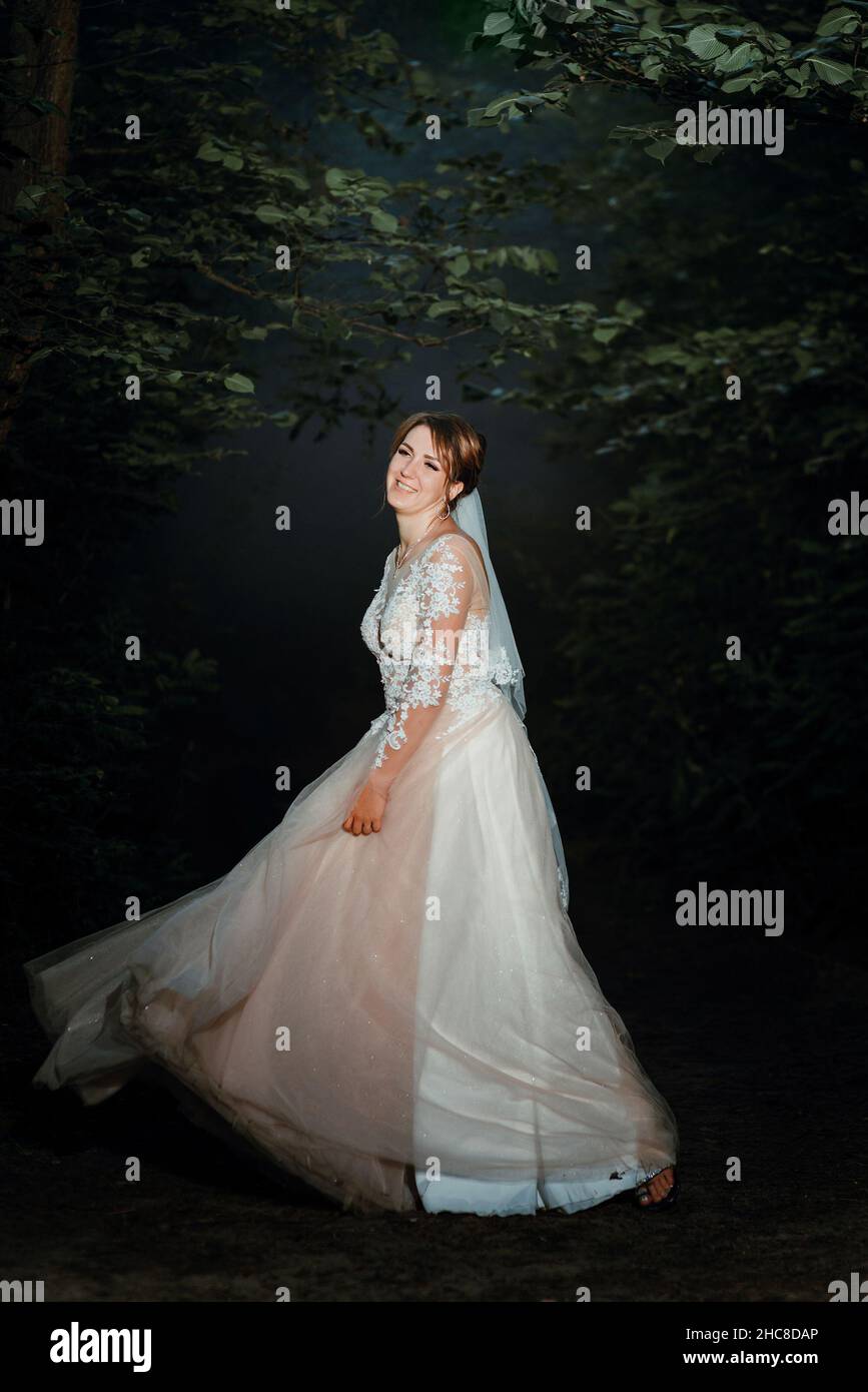Beautiful young bride in a magnificent wedding dress spinning in nature ...