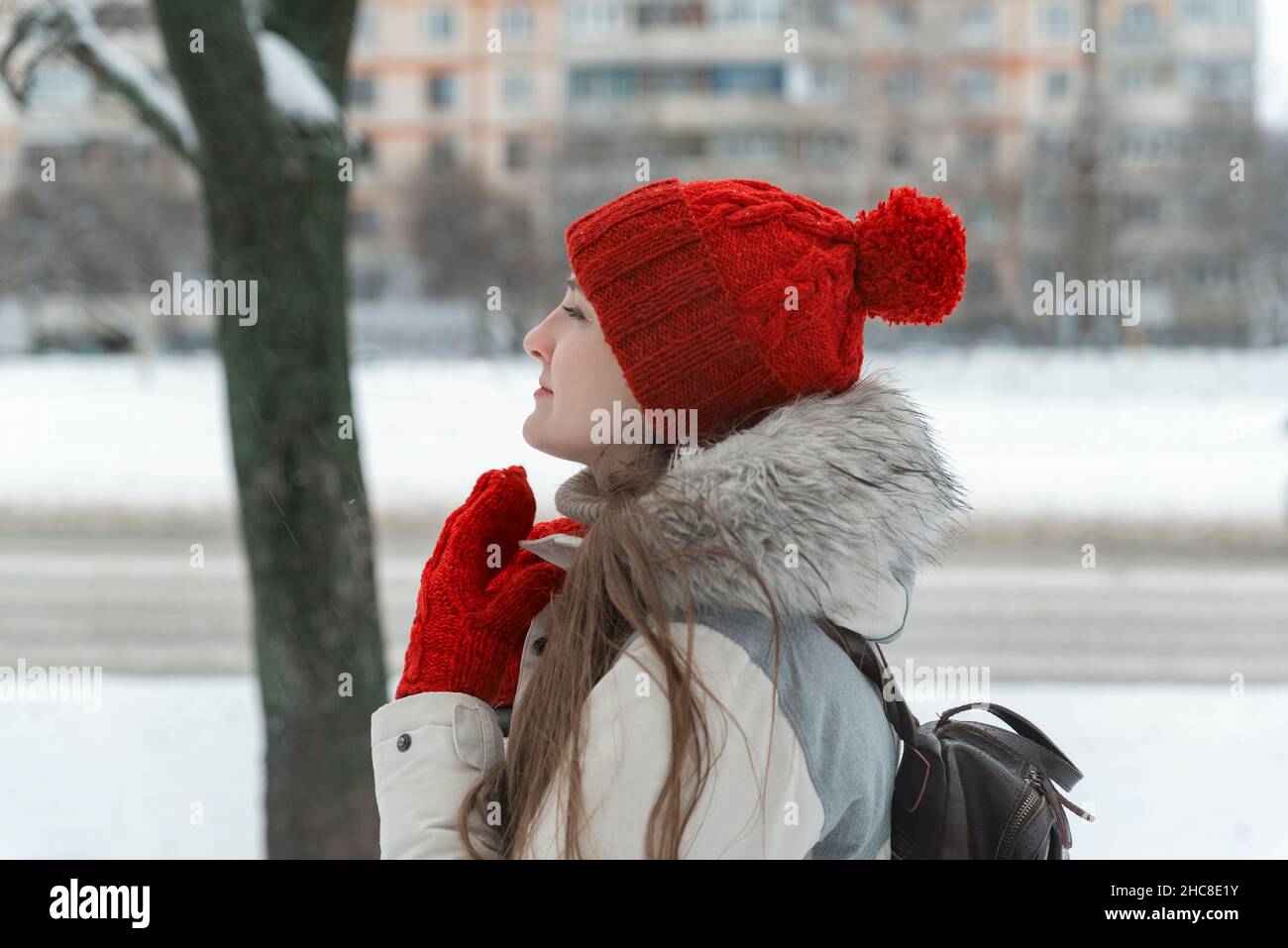Side view portrait of frozen woman in red hat and mittens on winter ...