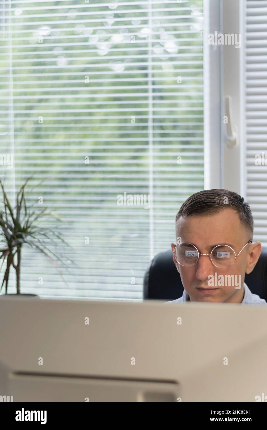 Man with glasses works in office and looks carefully at monitor. Office ...
