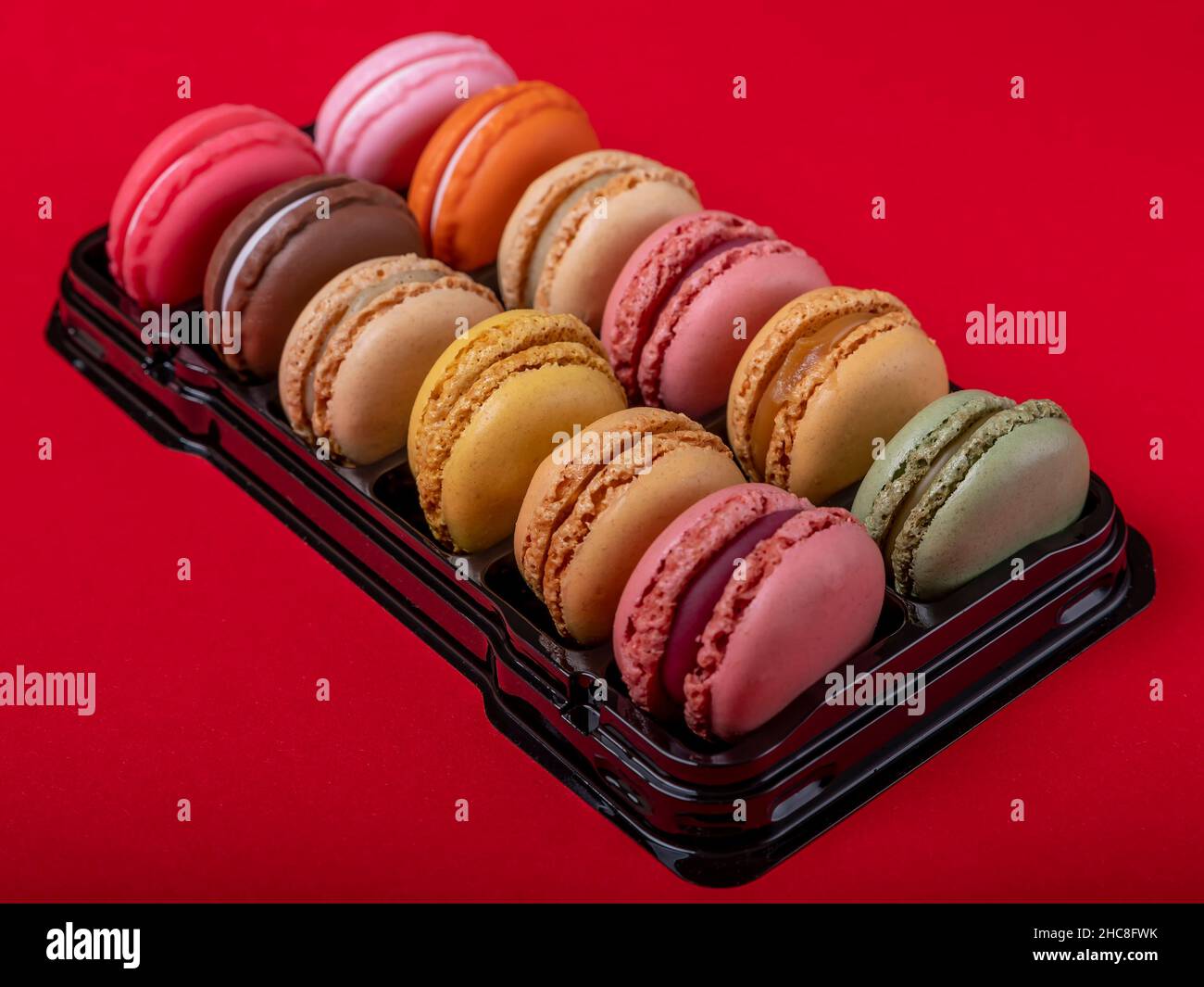 A tray of colorful and tasty macarons on a red background Stock Photo ...