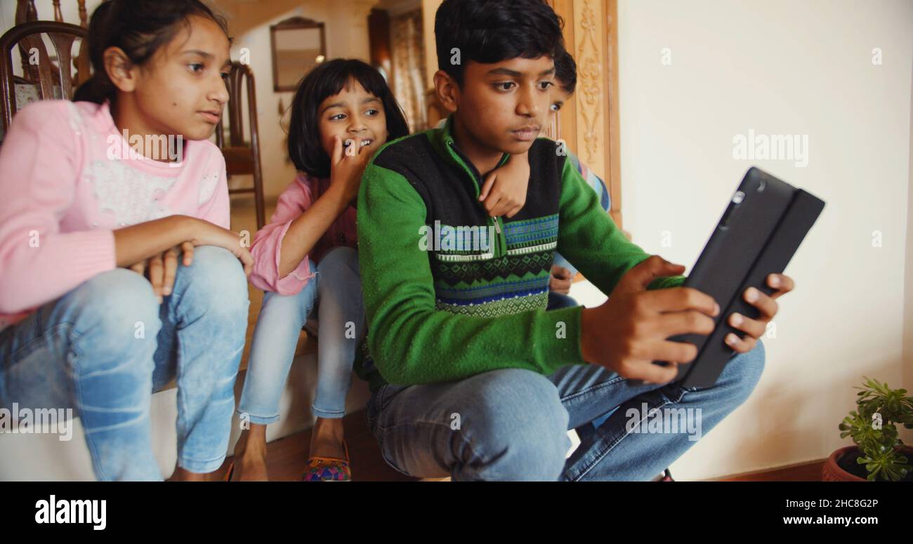 Beautiful shot of South Asian children playing a game with tablet Stock ...