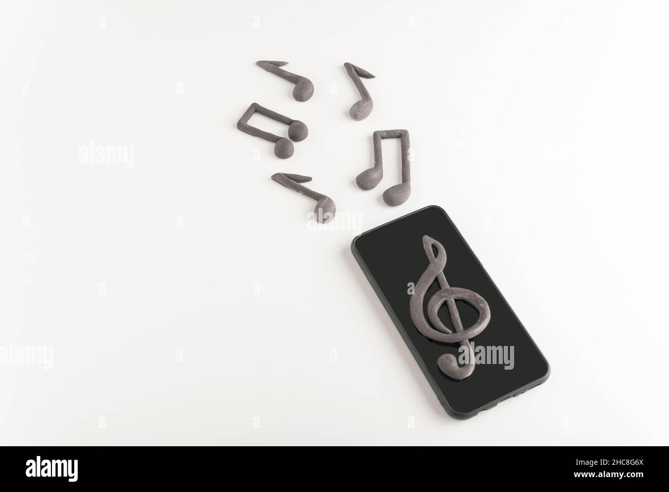Mobile phone with treble clef on display and musical notes on white ...