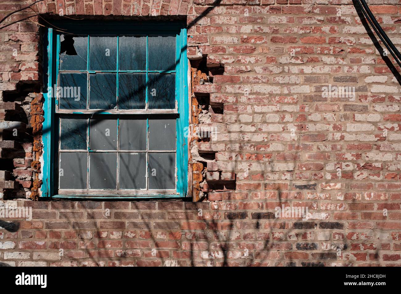 Colorful window with broken pane set in damaged brick wall with ...