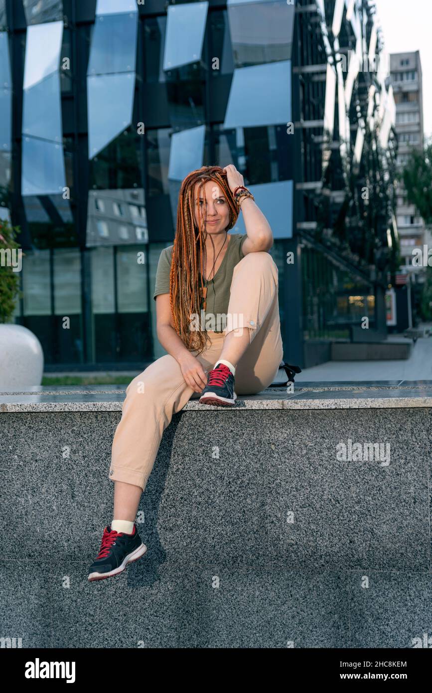 Girl with a cheerful look into the distance sitting on a parapet near ...