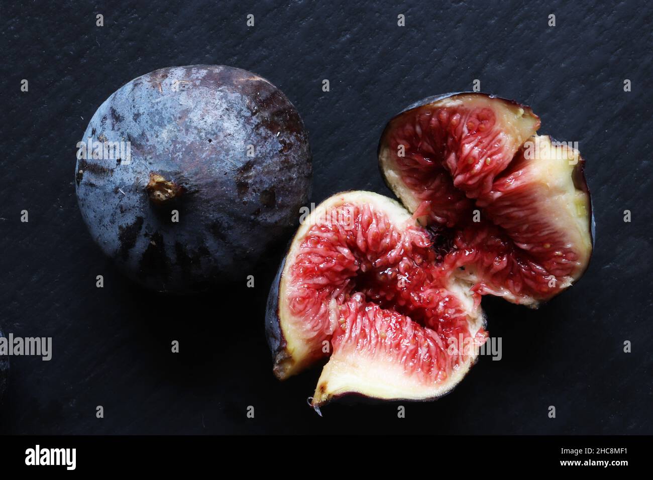 An open fresh red fig and a closed one on slate background for food ...