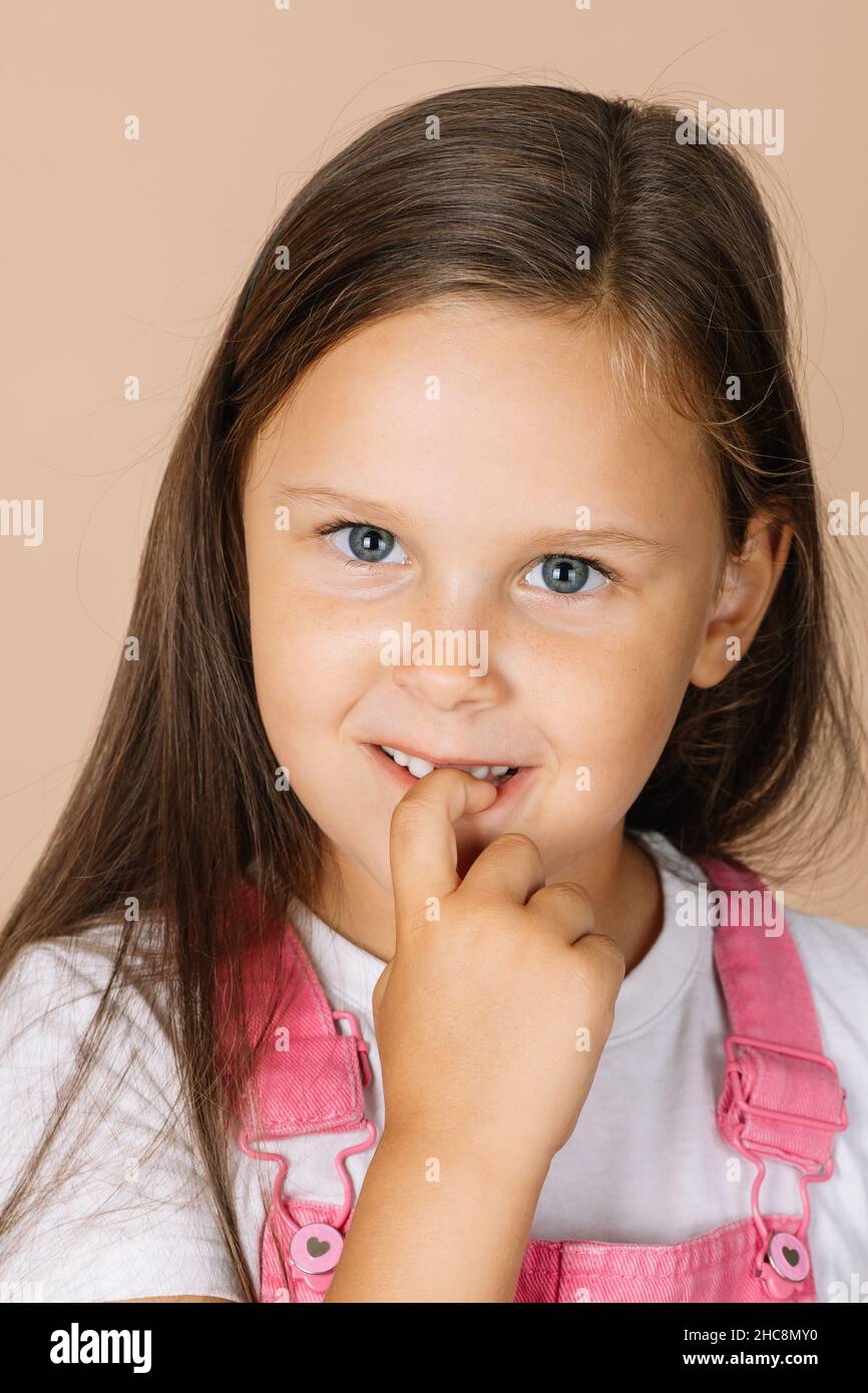 Little girl biting fingernails with shining eyes smiling looking at ...