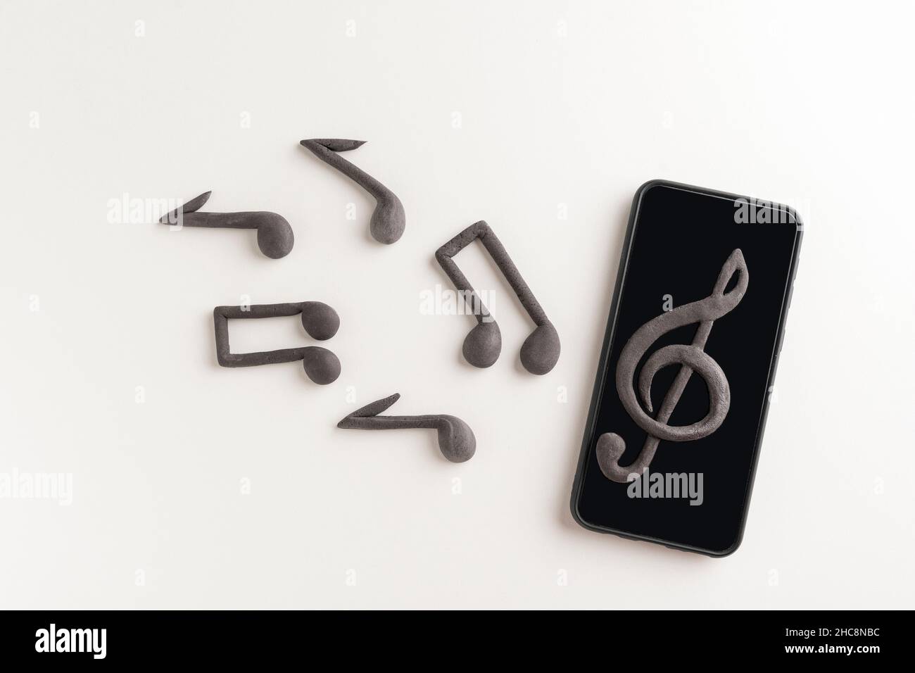 Smartphone phone with treble clef on display and musical notes on white ...