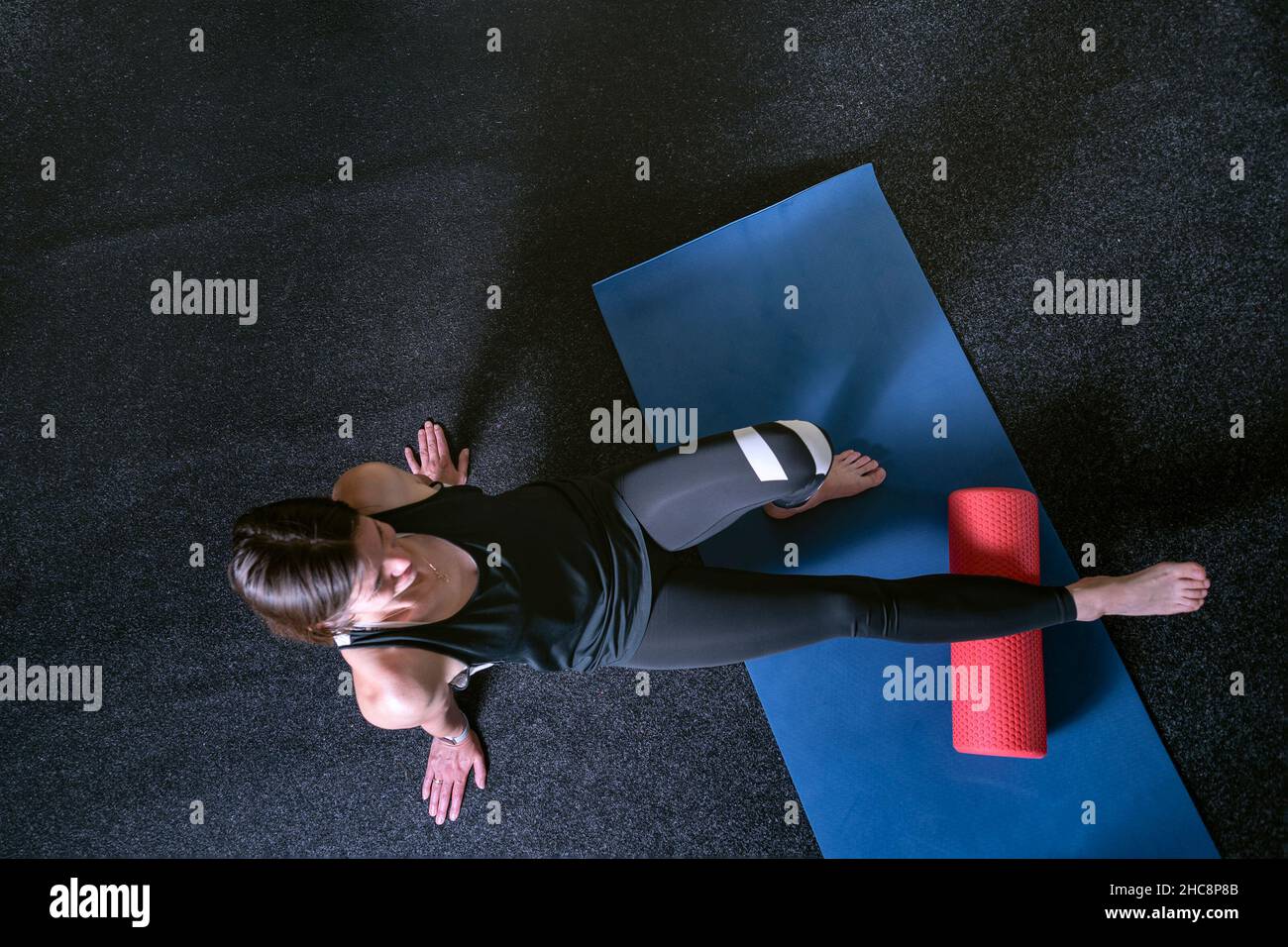 Athlete kneads the muscles of the legs with MFR roller. Top view ...