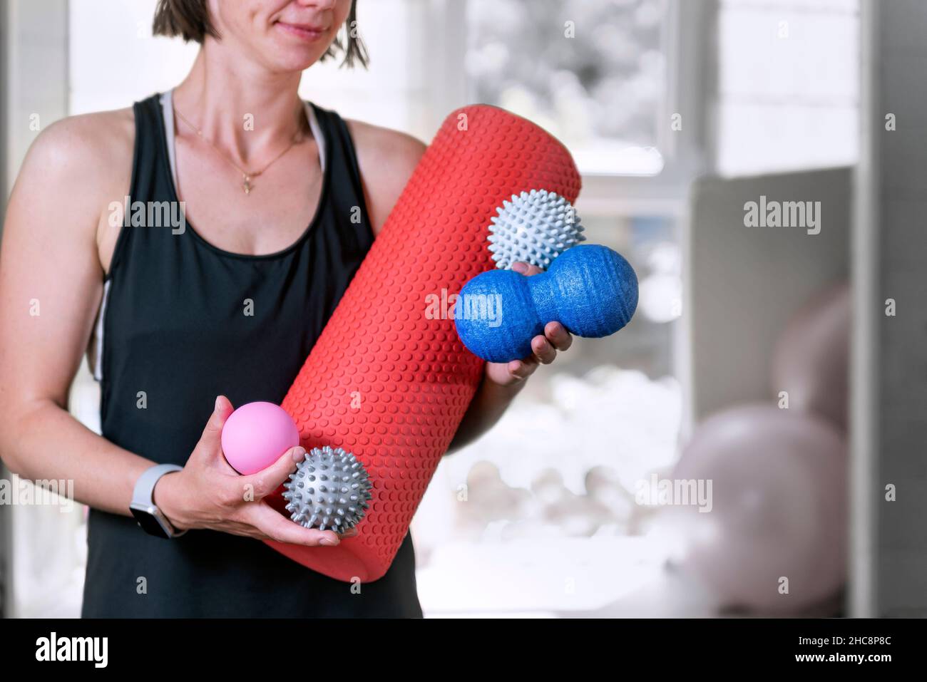 Young sportswoman in the gym stands with different types of myofascial ...