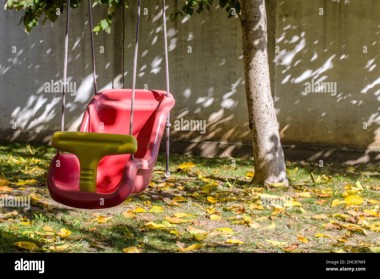 Plastic red swing for children hanging in the house yard Stock Photo ...