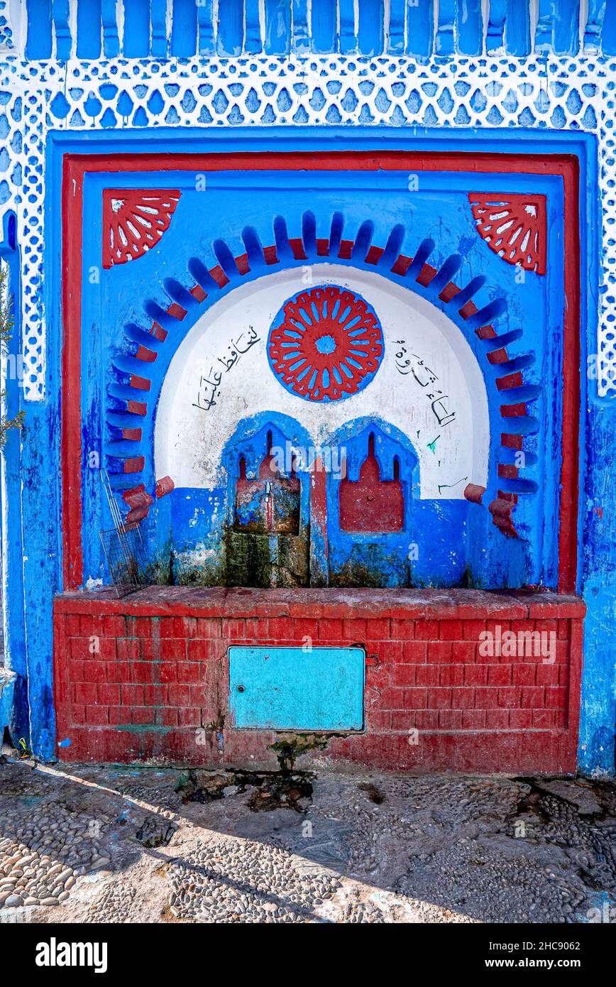Traditional water fountain and arabic text written on wall of building ...