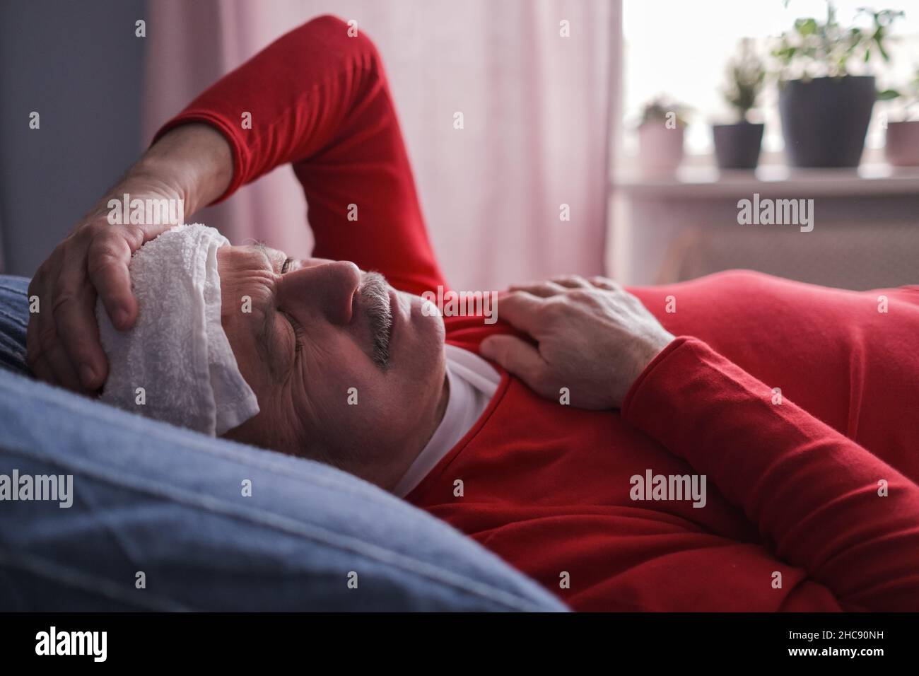 A sick male sleeping with wet towel on his forehead to reduce high high ...