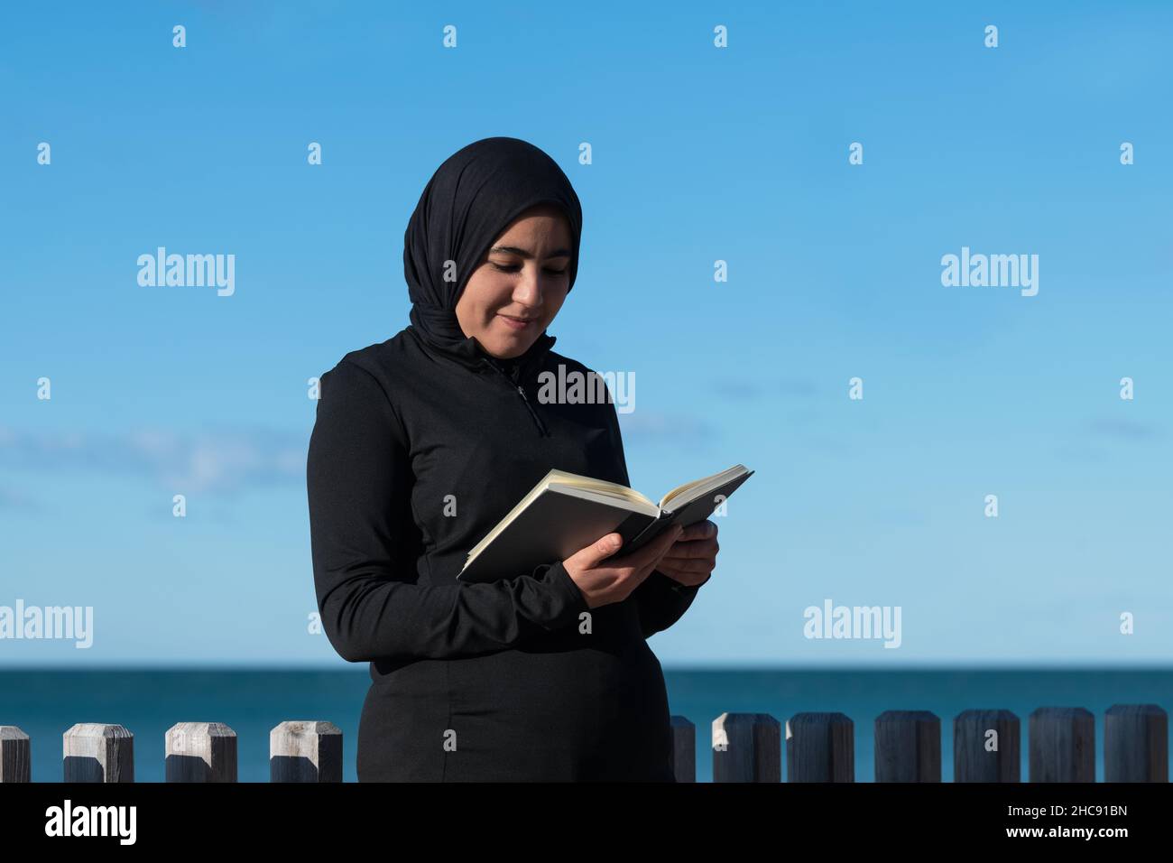 Smiling muslim woman enjoying a book outdoors Stock Photo - Alamy