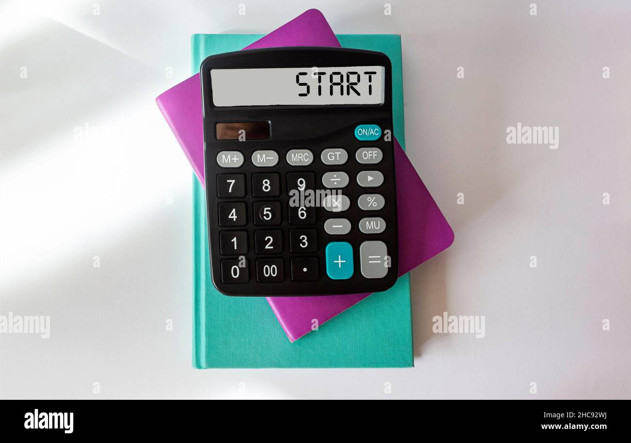 Start text on calculator display with notepads on white background ...