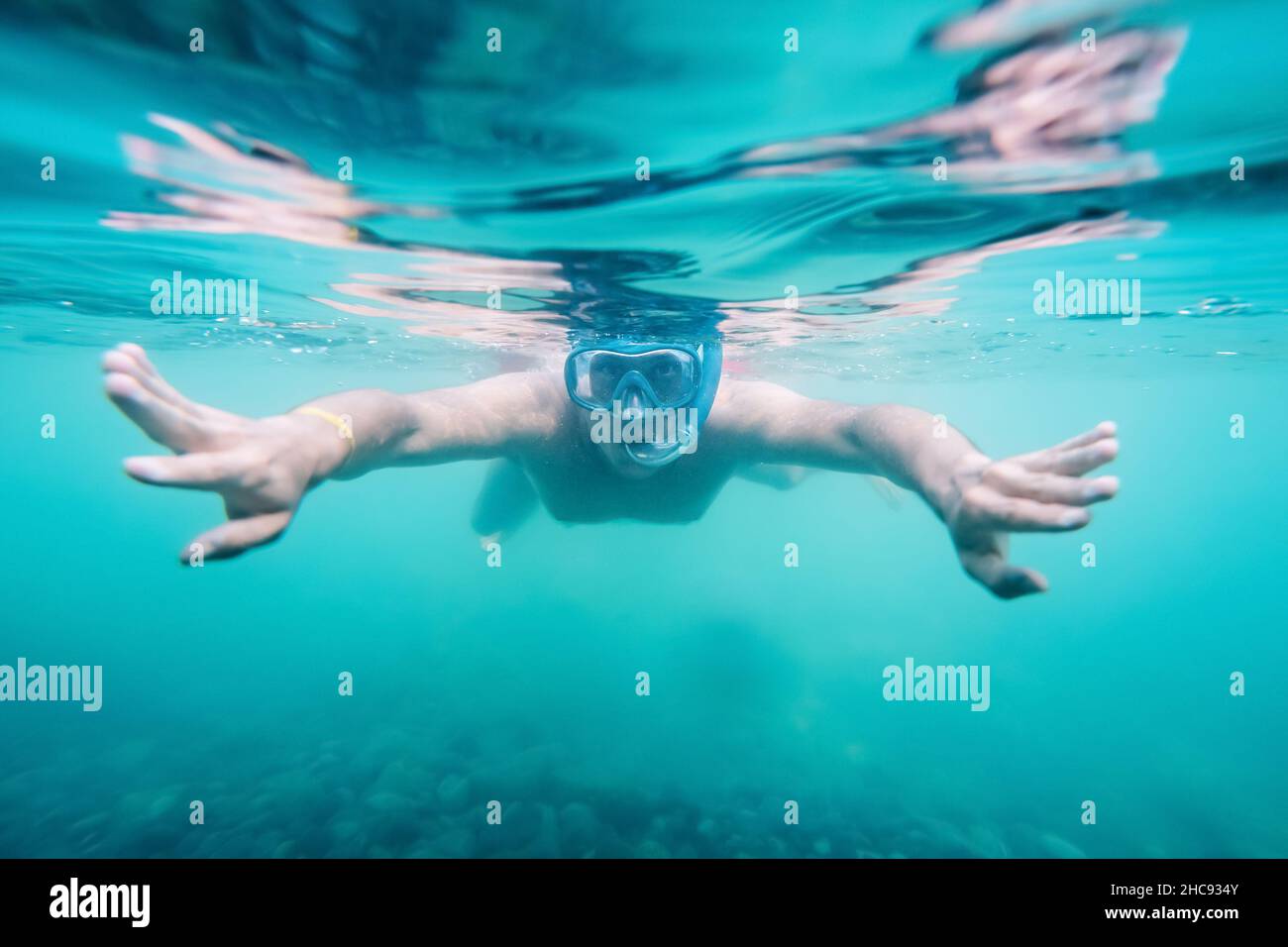 A young and happy man enjoys snorkeling underwater at an amateur level ...