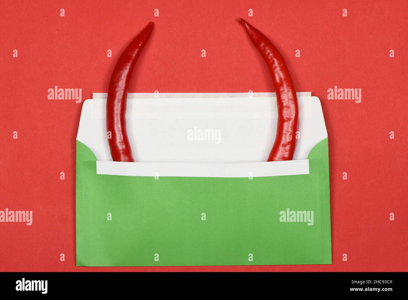Red chili pepper in a mailing envelope isolated on a red background ...