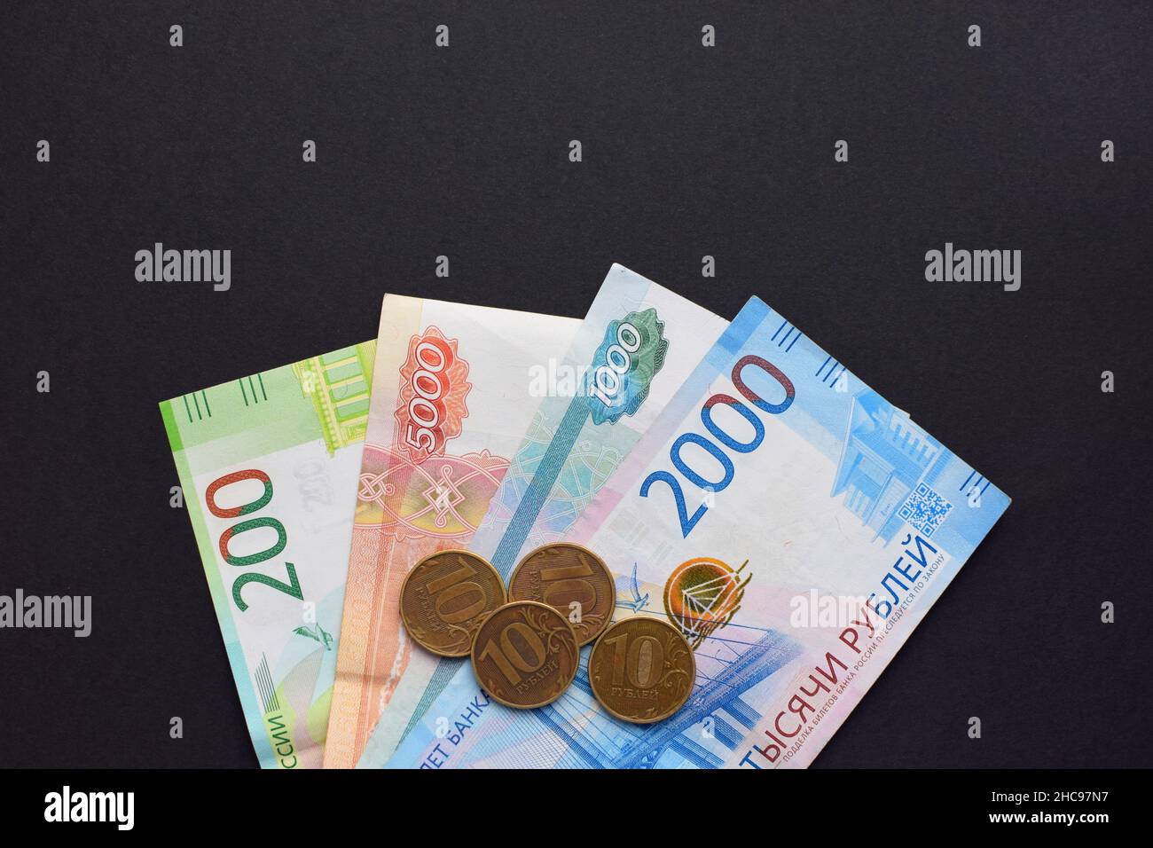 Russian rubles on a black background. Thousand notes and various coins ...