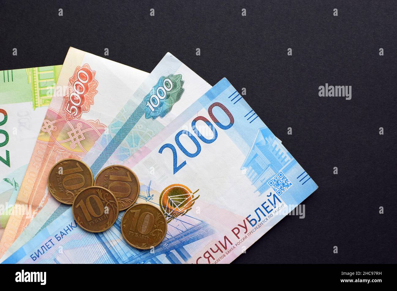 Russian rubles on a black background. Thousand notes and various coins ...