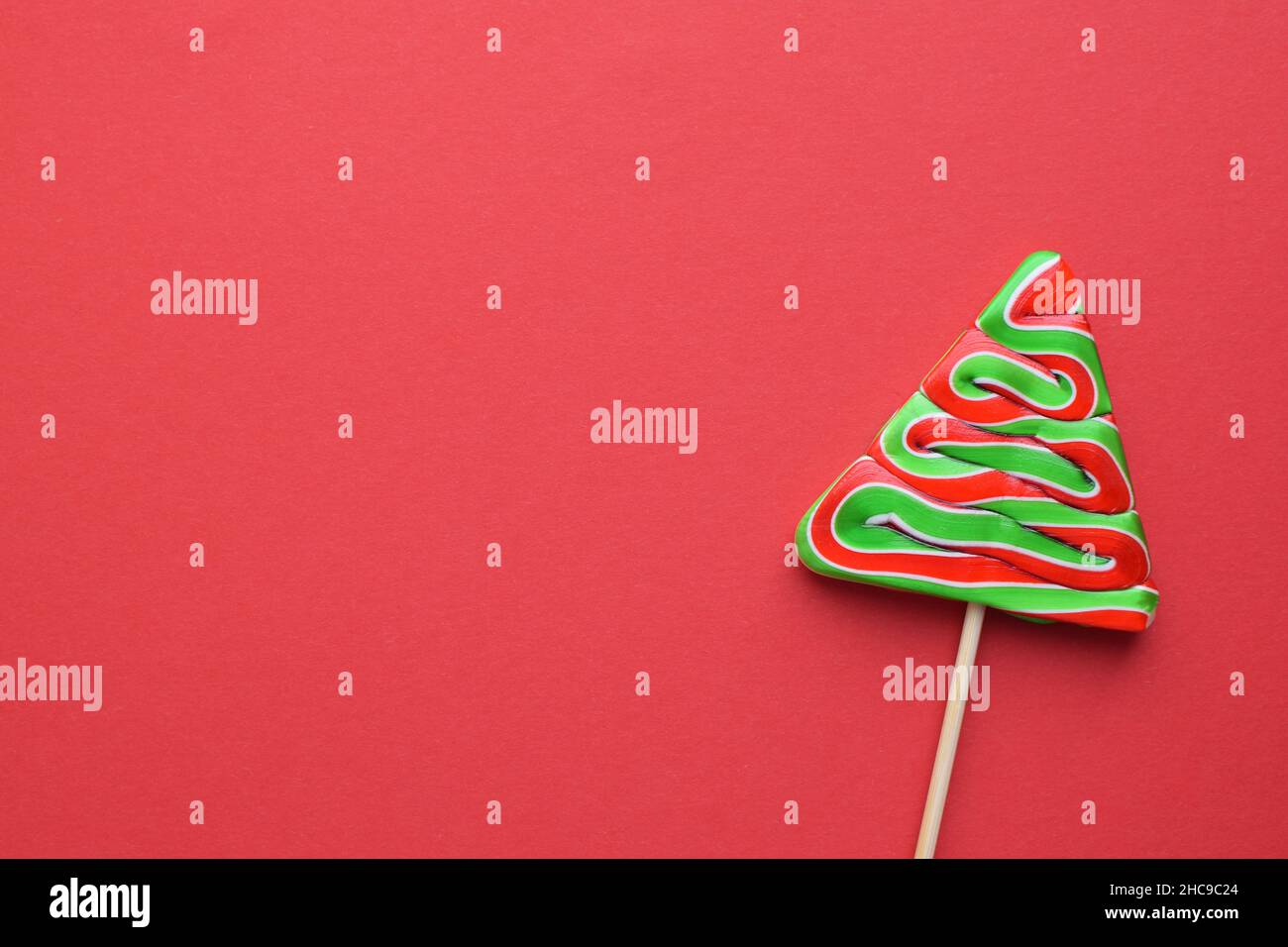 Lollipop in the shape of a christmas tree and red background. Copy ...