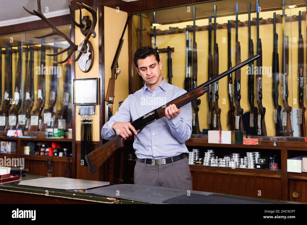 Handsome adult male owner of hunting shop offering rifle Stock Photo ...