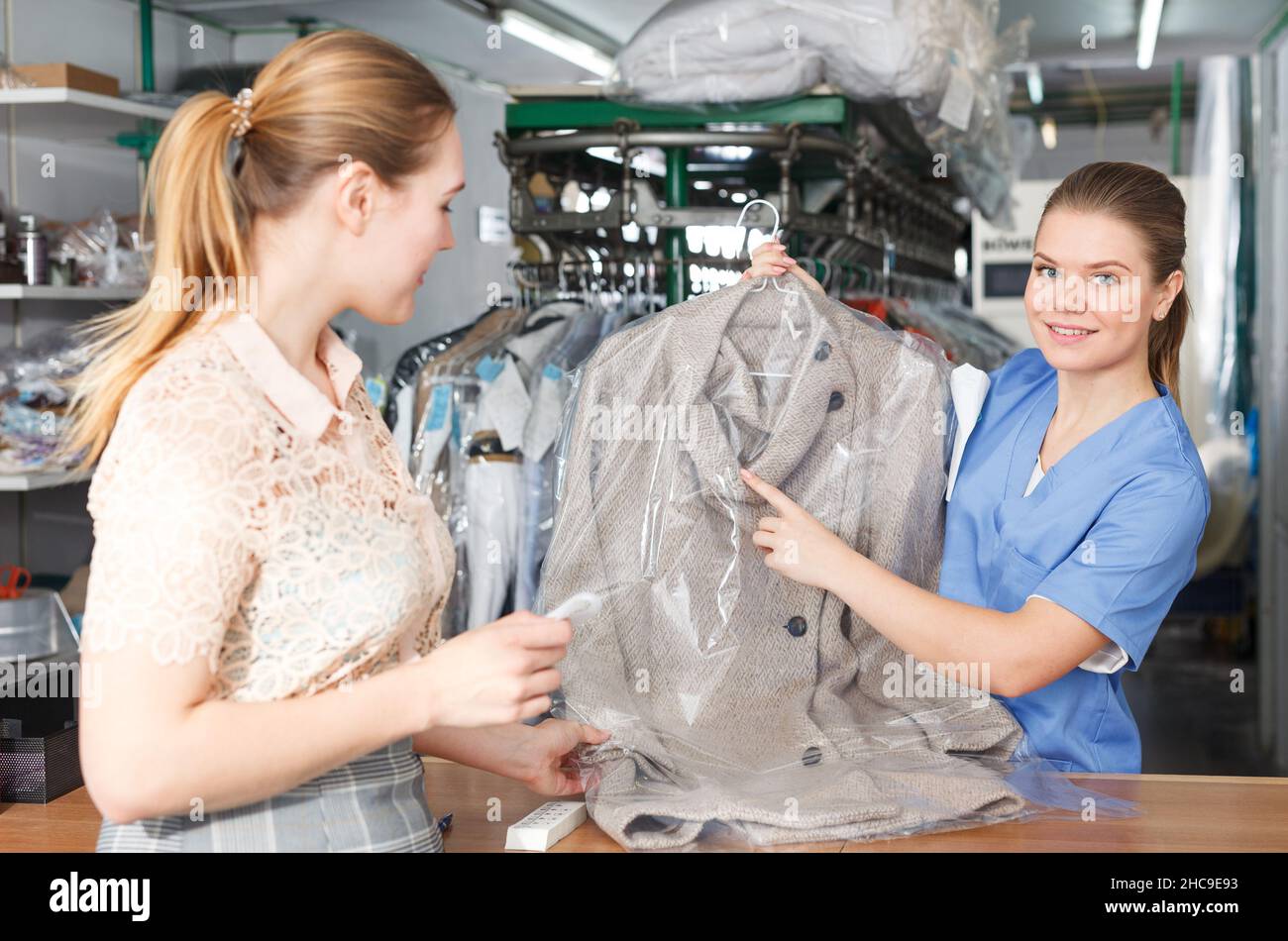 Laundry worker giving clean clothes to client Stock Photo - Alamy