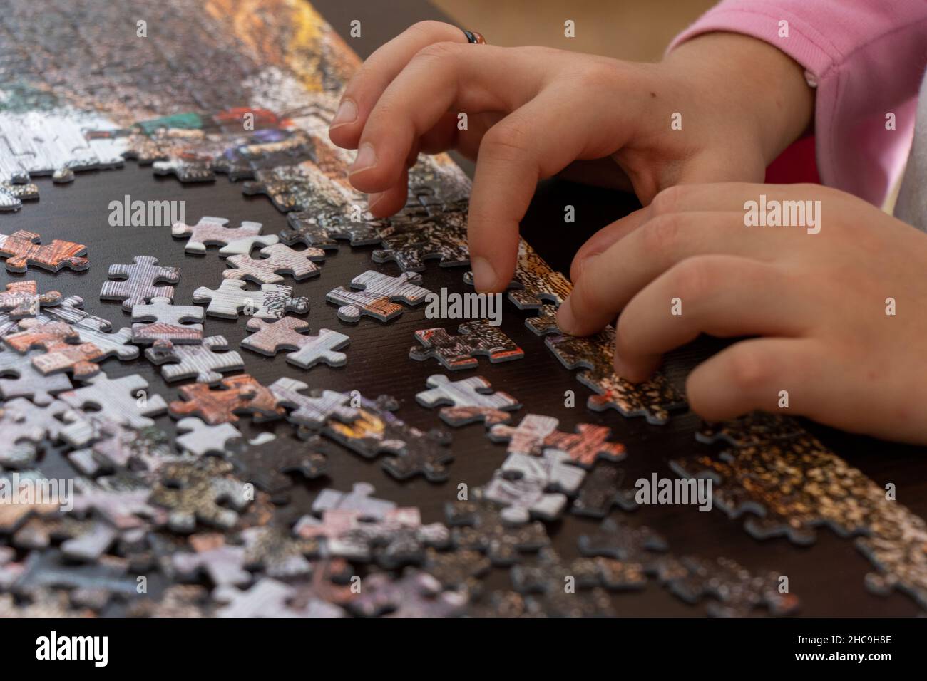Little girl doing jigsaw puzzle at home. Close up photo with selective ...