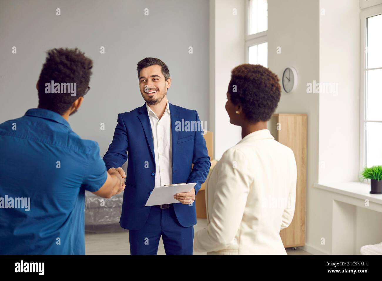 Friendly male estate agent shaking hands with customer indoors Stock ...