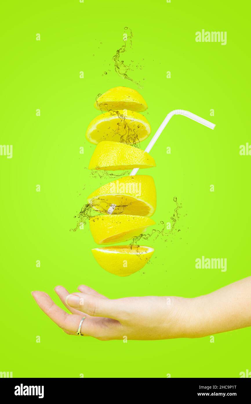 A cut lemon in levitation flies slices freely with straw and splash on ...