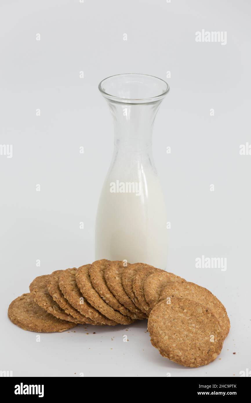 milk bottle and cookies fallen in front, all on a white background ...