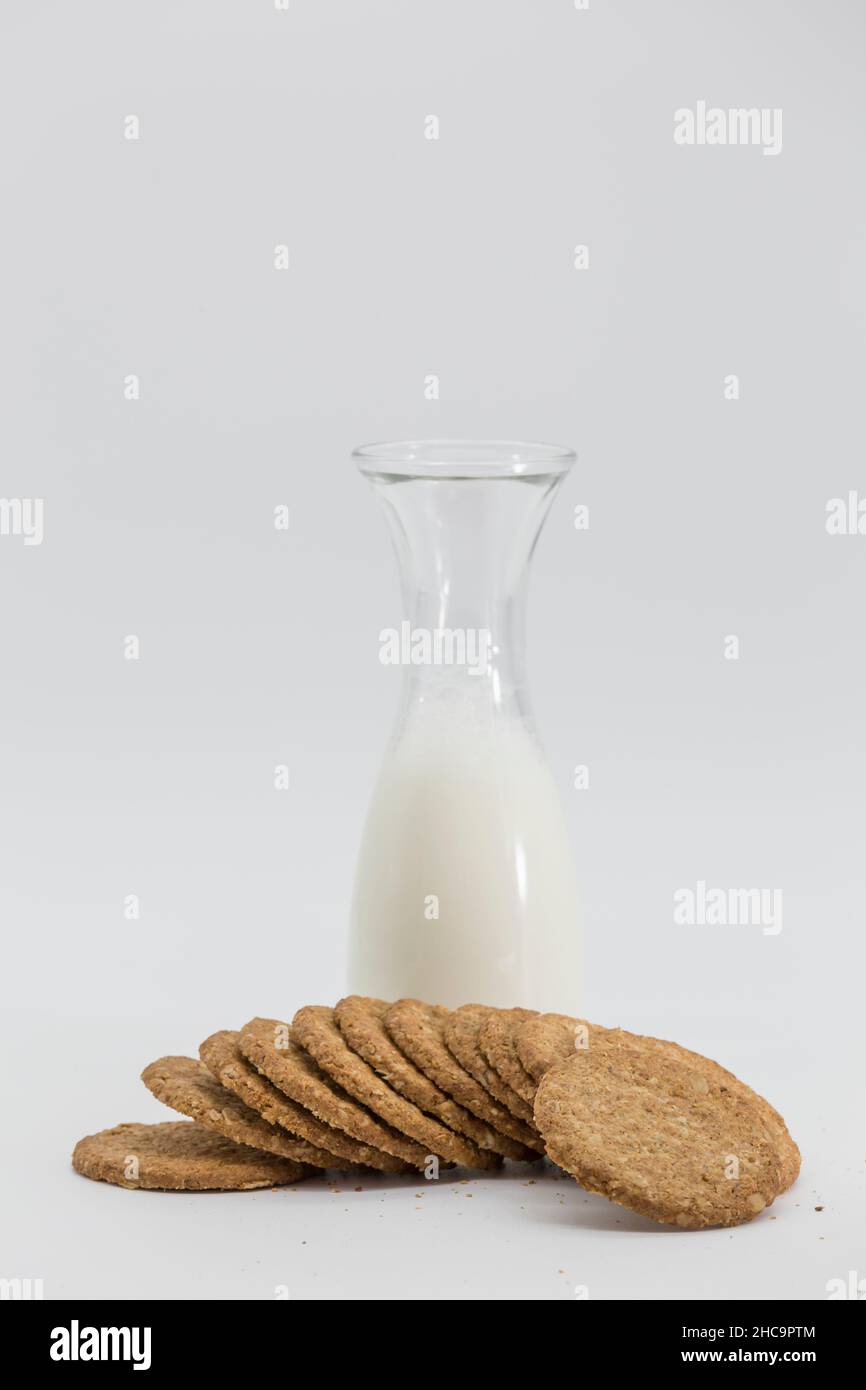 milk bottle and cookies fallen in front, all on a white background ...